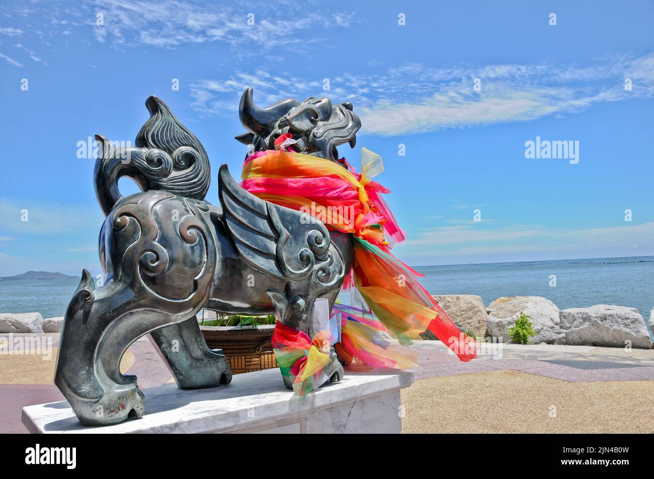 Dark metallic bronze brass black metal Asian lion statue with vast blue ...