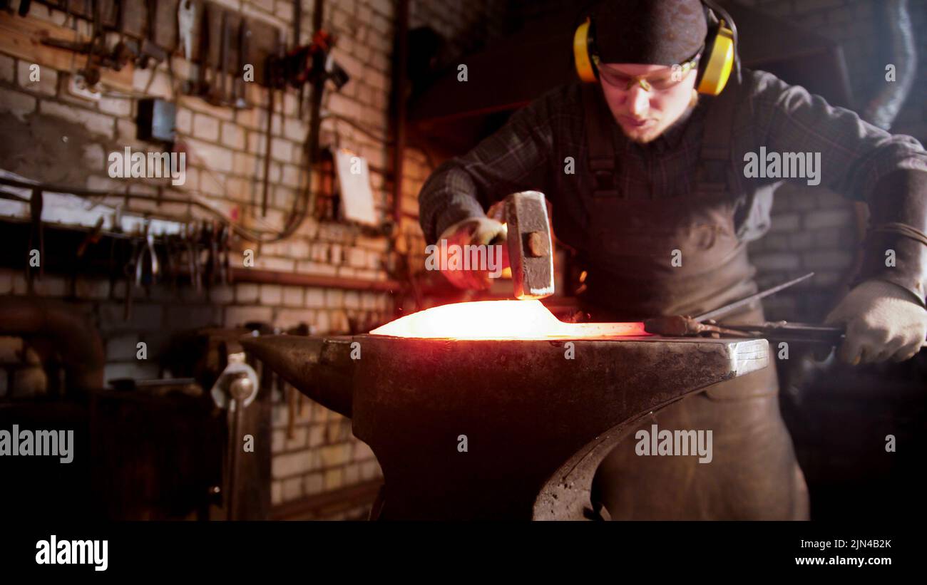 Blacksmith forging a knife blade in his workshop using a hammer Stock ...