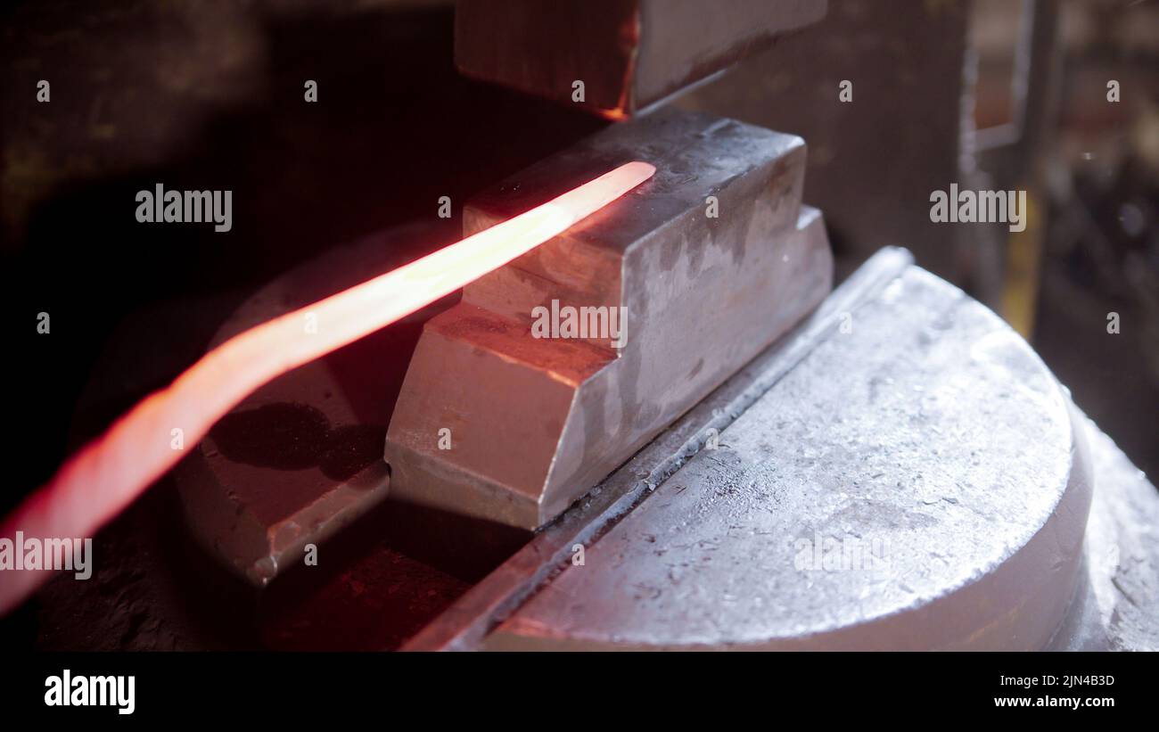 Blacksmith making a longer piece of metal under the machine pressure ...