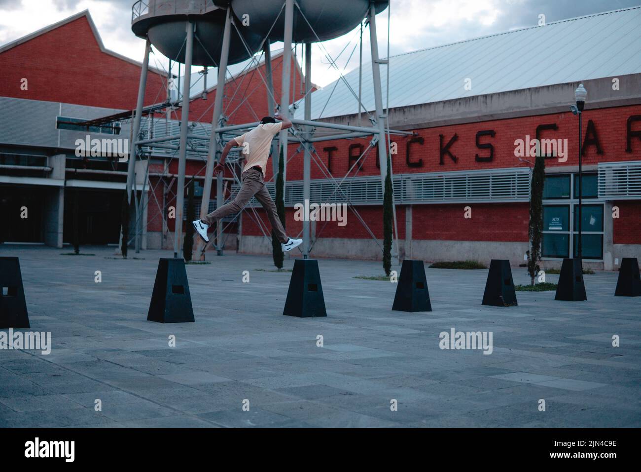 Latin young man in the middle of a parkour jump in obstacles in a ...