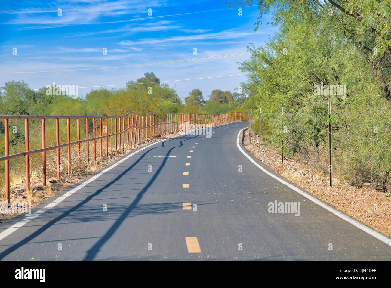 Concrete bicycle trail with yellow lanes at Sweetwater Wetlands- Tucson, Arizona. Concrete bike ...