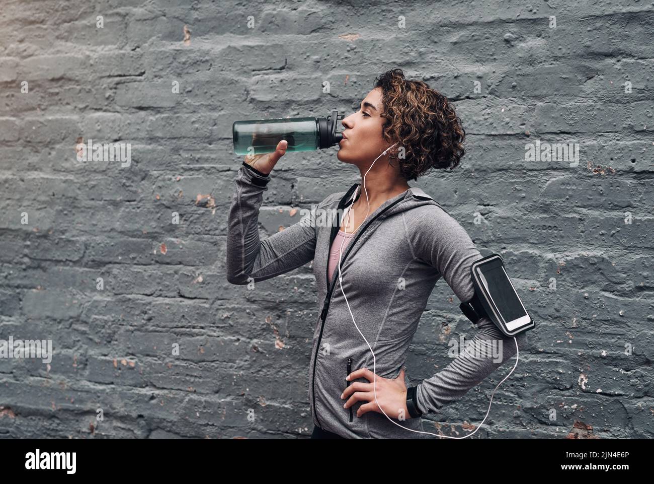 Staying hydrated during a workout. a young woman taking a water break ...