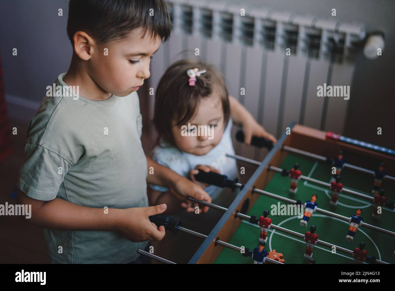 Big brother spending playtime with his younger sister playing foosball ...