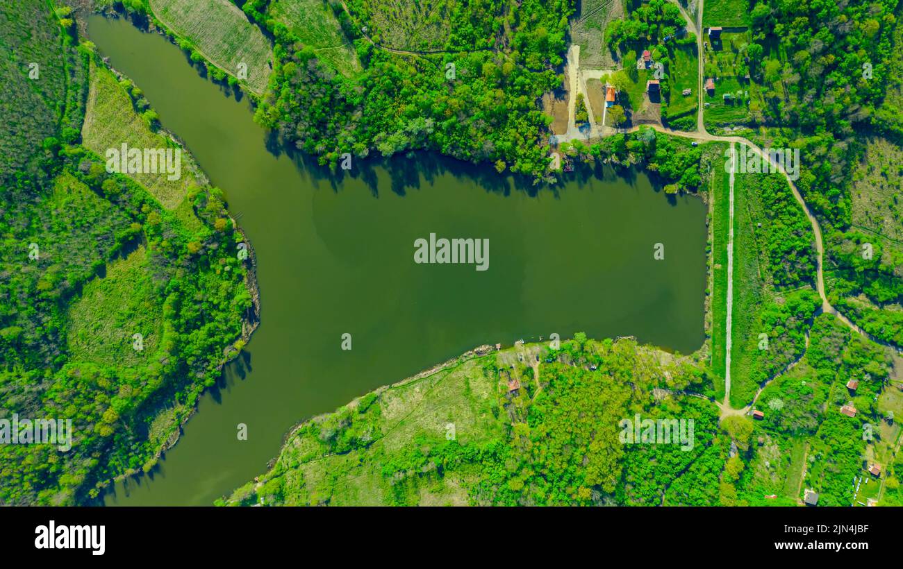 Above top view, overhead, on the end of the lake surrounded by green ...