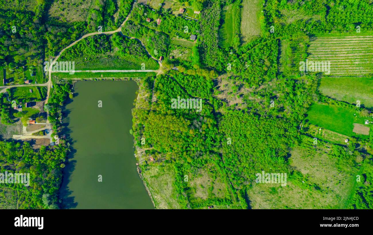 Above top view, overhead, on the end of the lake surrounded by green ...