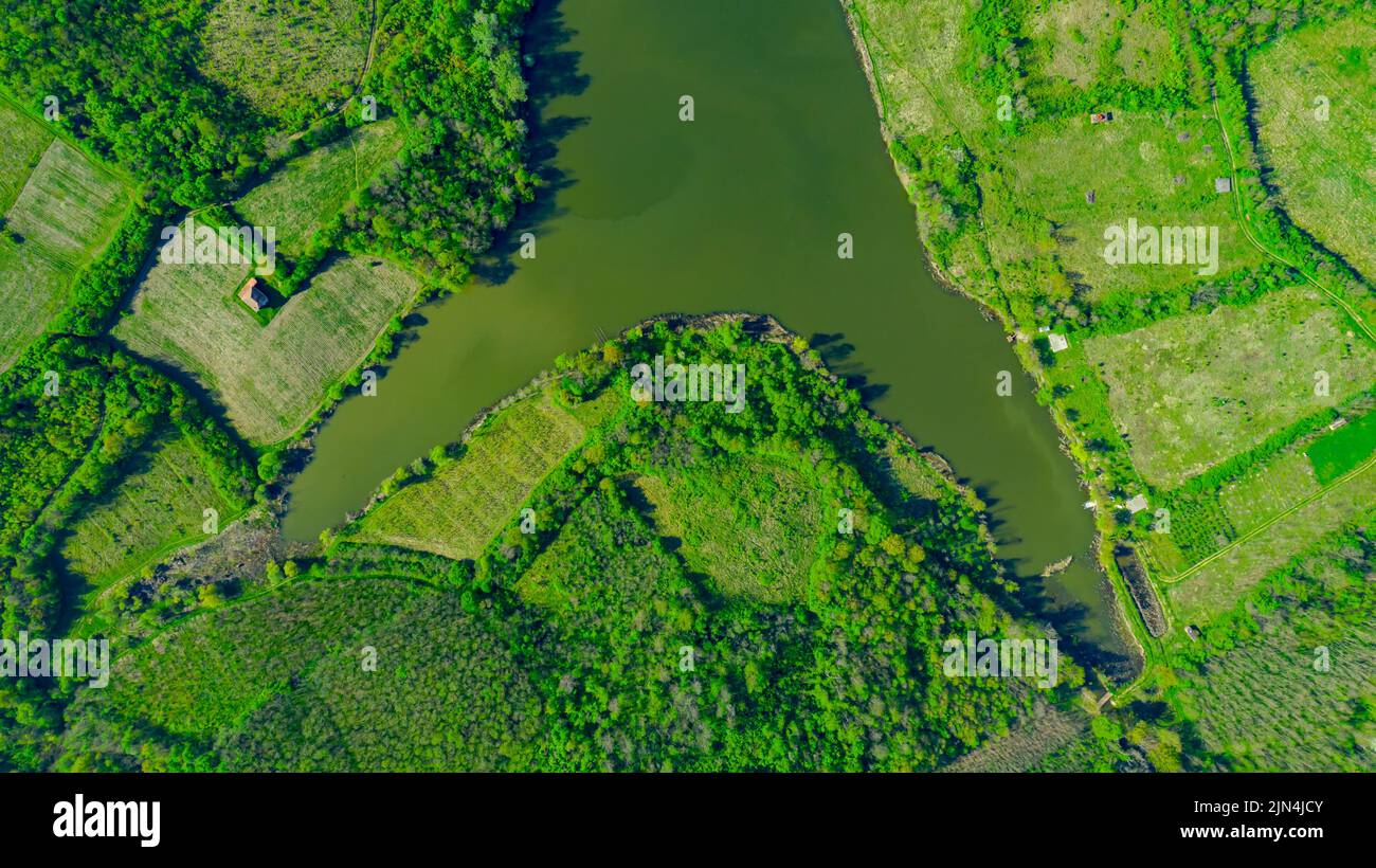 Above top view, overhead, on the end of the lake surrounded by green ...