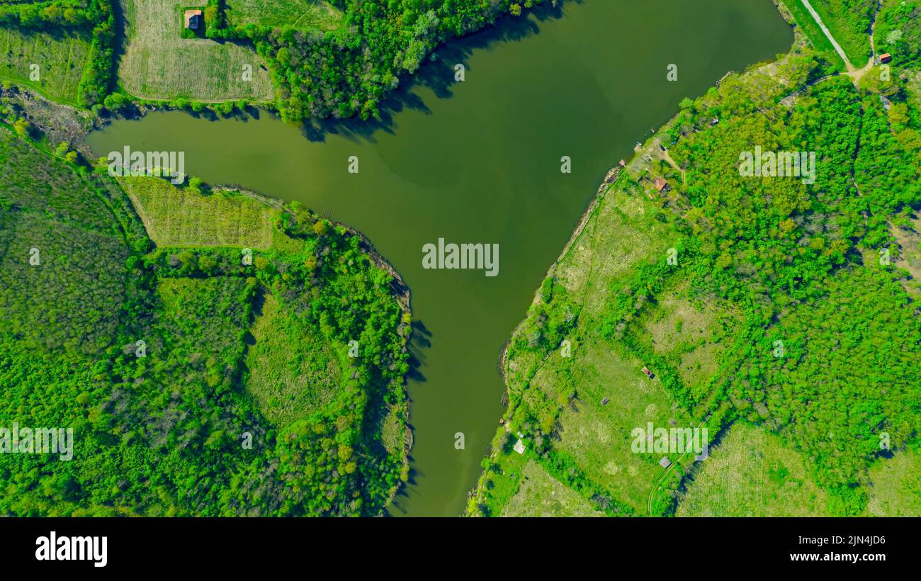 Above top view, overhead, on the end of the lake surrounded by green ...