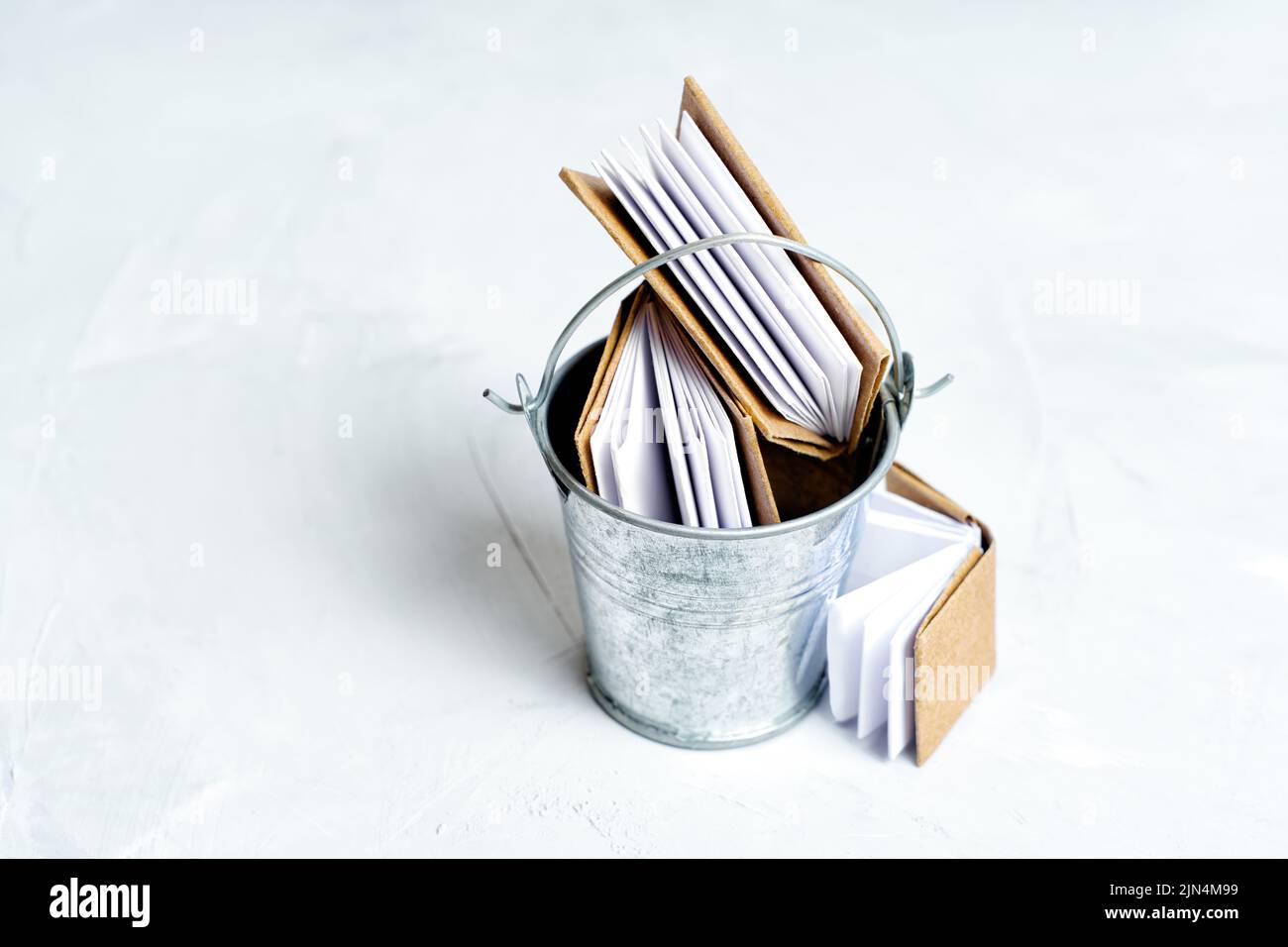 Three miniature hand-made books in a small steel bucket isolated on a ...
