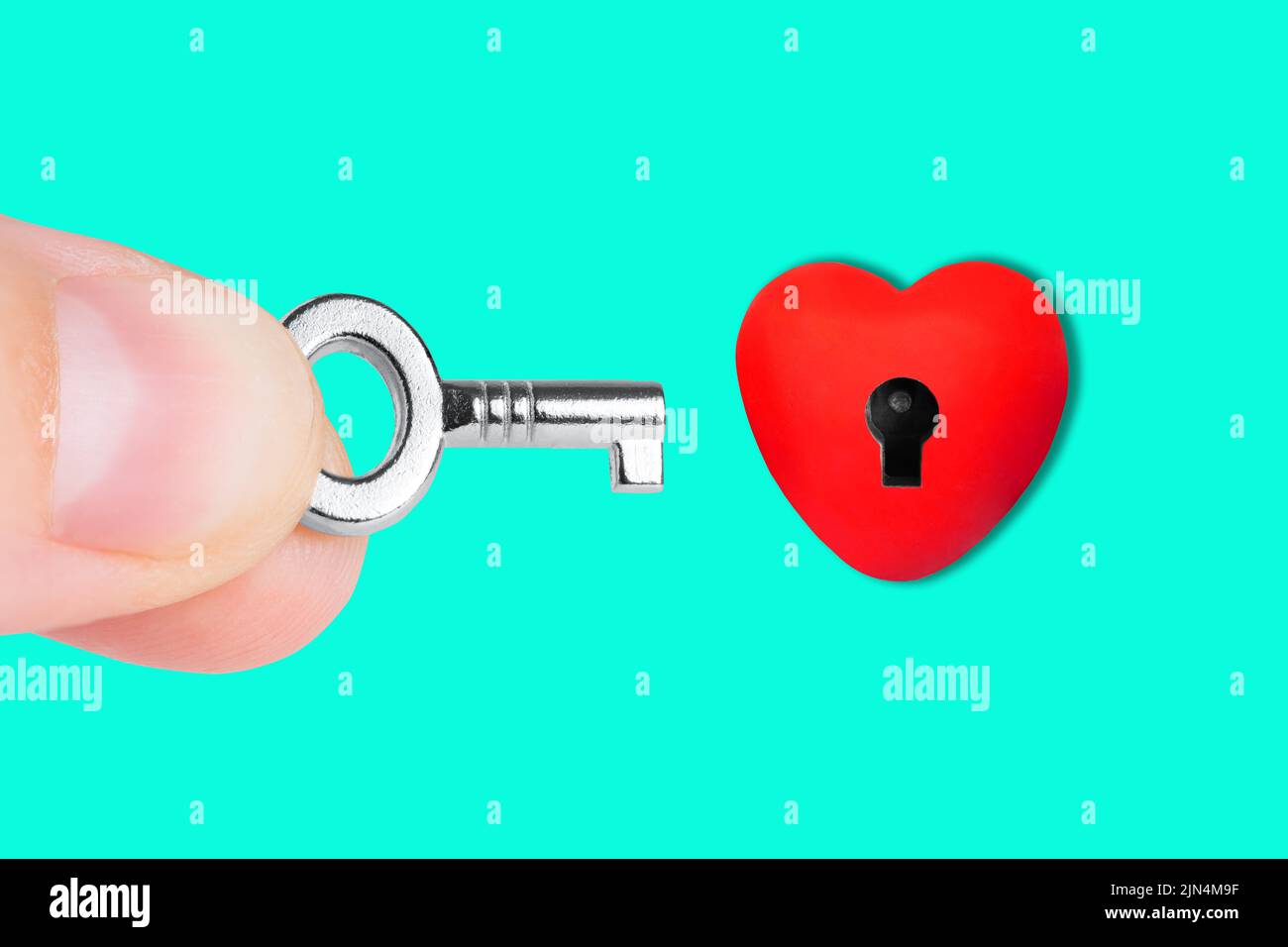 Pinch holding a small skeleton key trying to open a red heart with a ... Pinch holding a small skeleton key trying to open a red heart with a ...