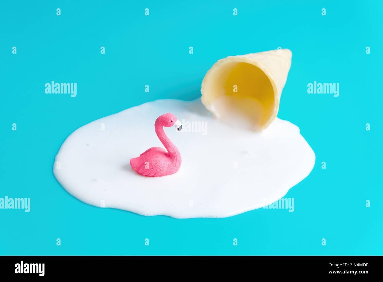 Pink flamingo figurine in a melted waffle cone ice cream puddle ...