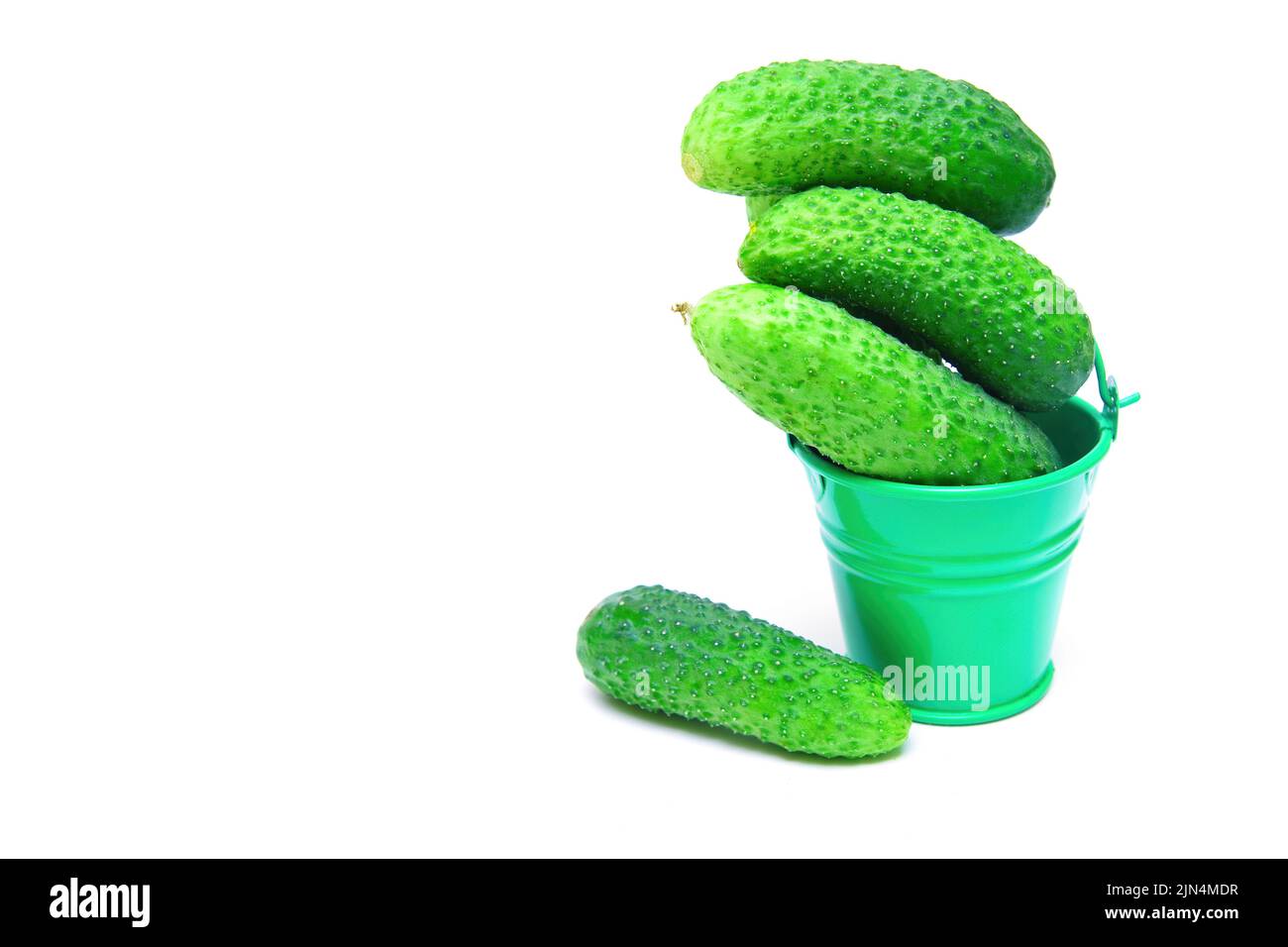 Pile of fresh cucumbers in a miniature green bucket isolated on white ...