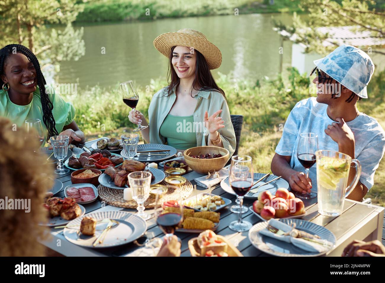 Diverse group of friends laughing and chatting at table during dinner ...