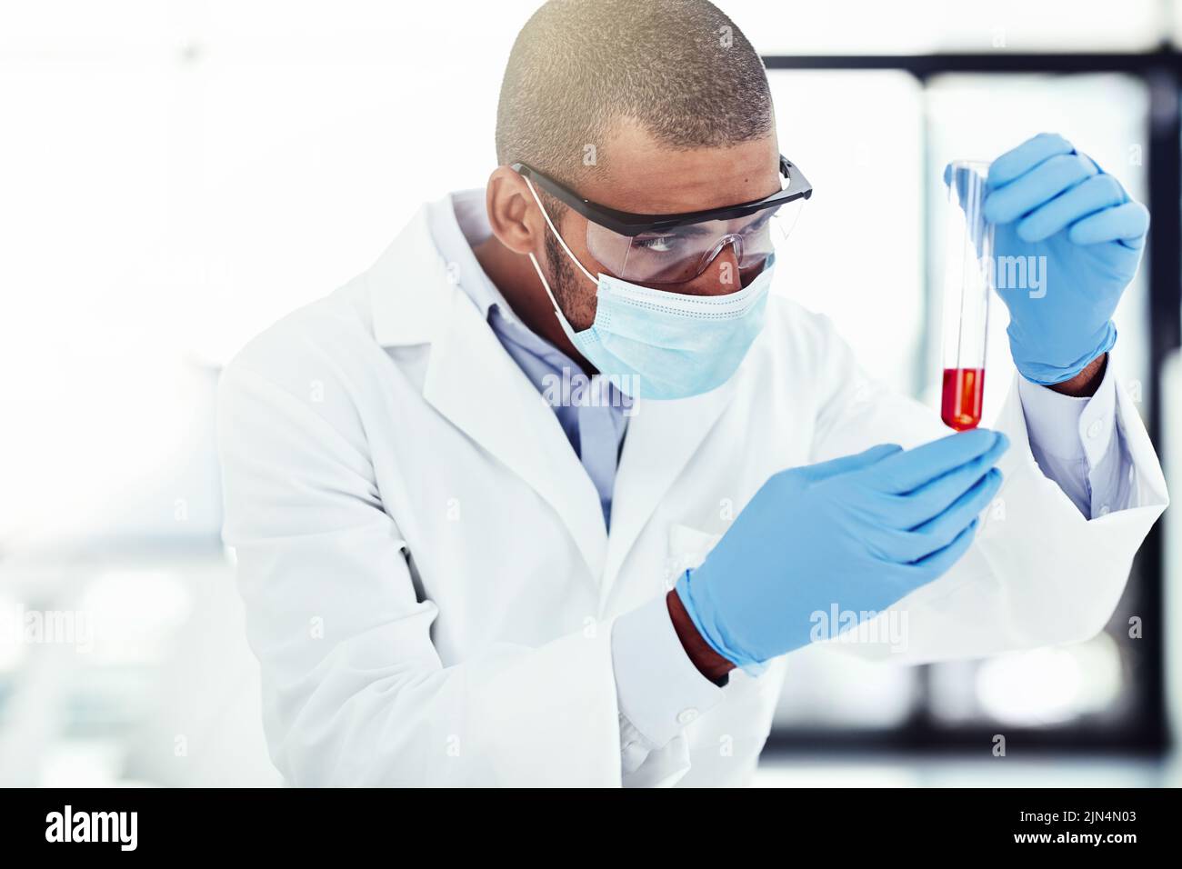 Curious, serious and thinking scientist with test tube solution and ...