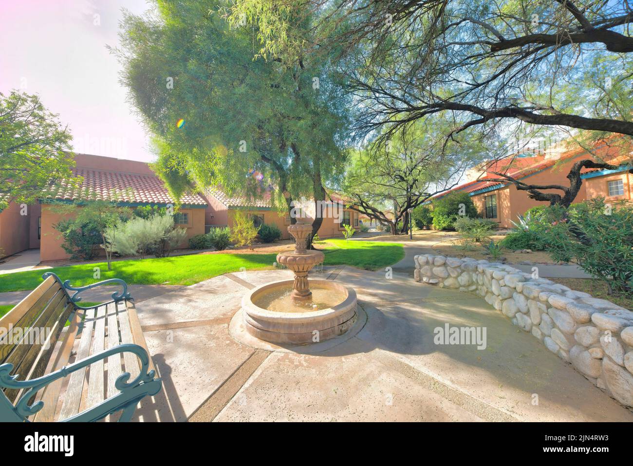 Small lounge area with bench and fountain outside the houses with peach ...
