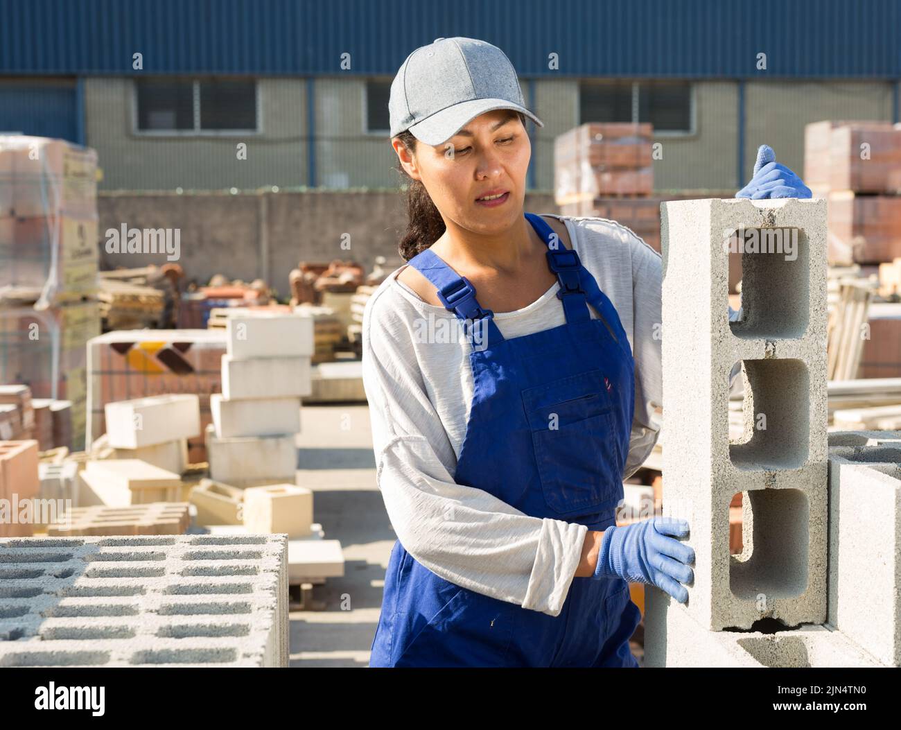 Asian worker stacking bricks in warehouse of building materials on an ...