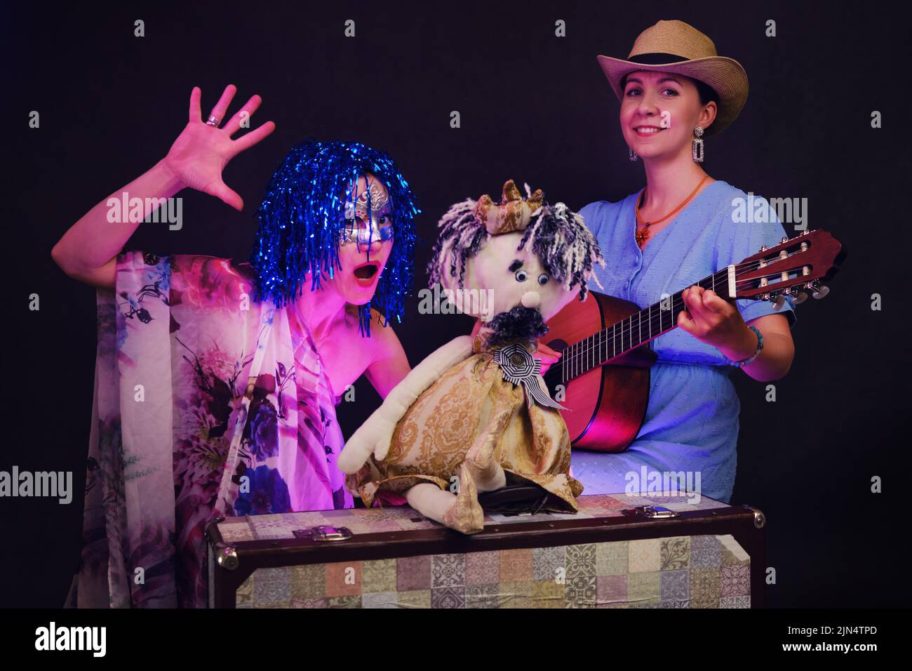 Happy women in funny wigs give a musical performance on a studio black ...
