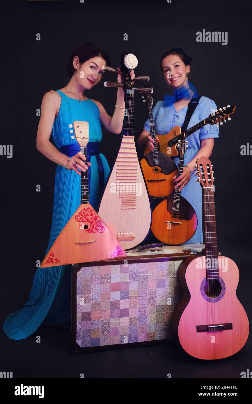 Women musicians in blue dresses with musical instruments on a black ...