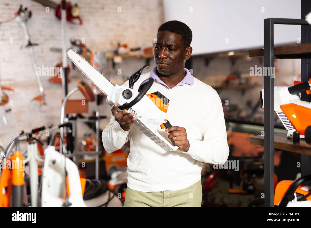 African american man chooses chainsaw at garden tool store Stock Photo ...