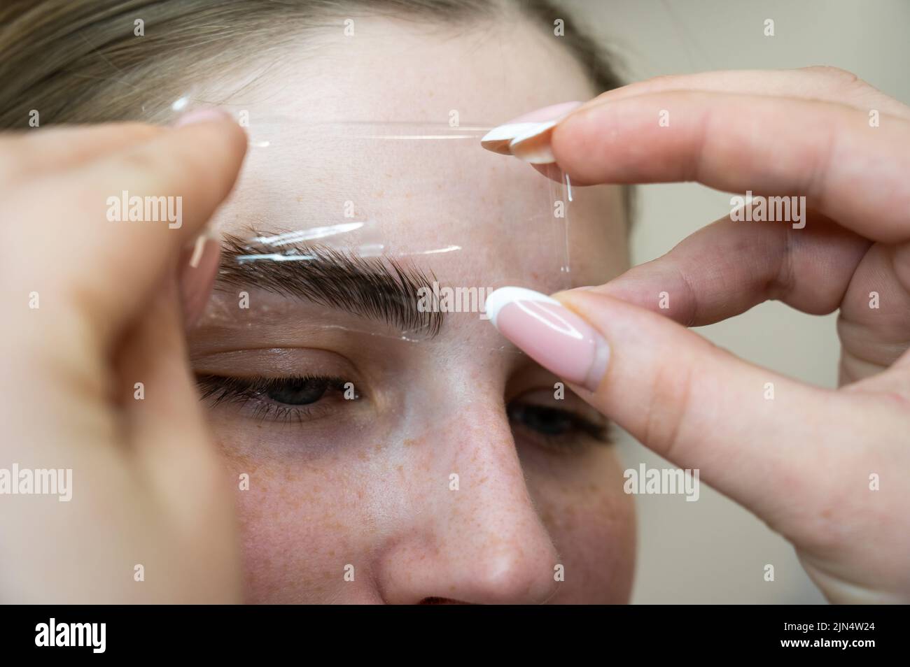The master uses a plastic film during lamination of the eyebrows Stock ...