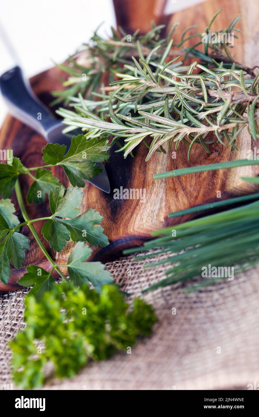 Close up of various herbs on a wooden chopping board - shallow dof ...