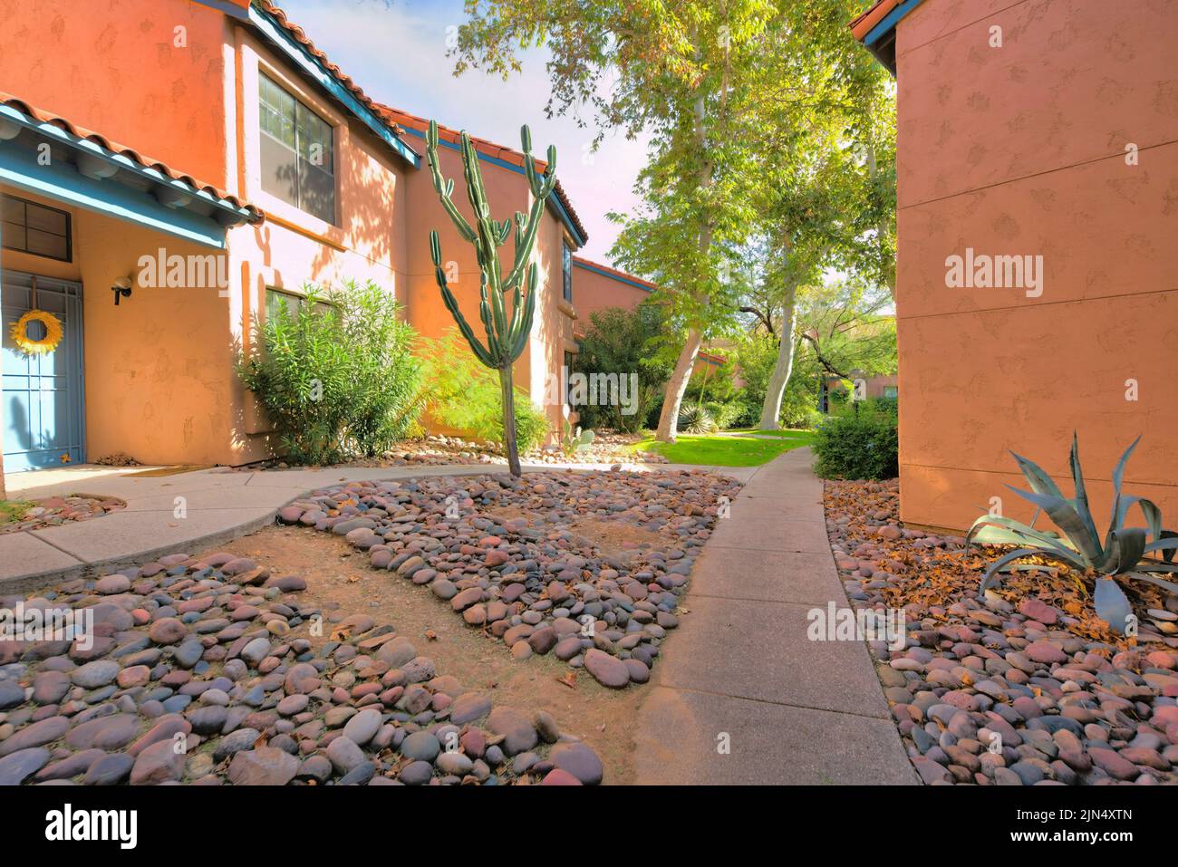 Concrete pathway leading to the front doors of the houses with peach ...