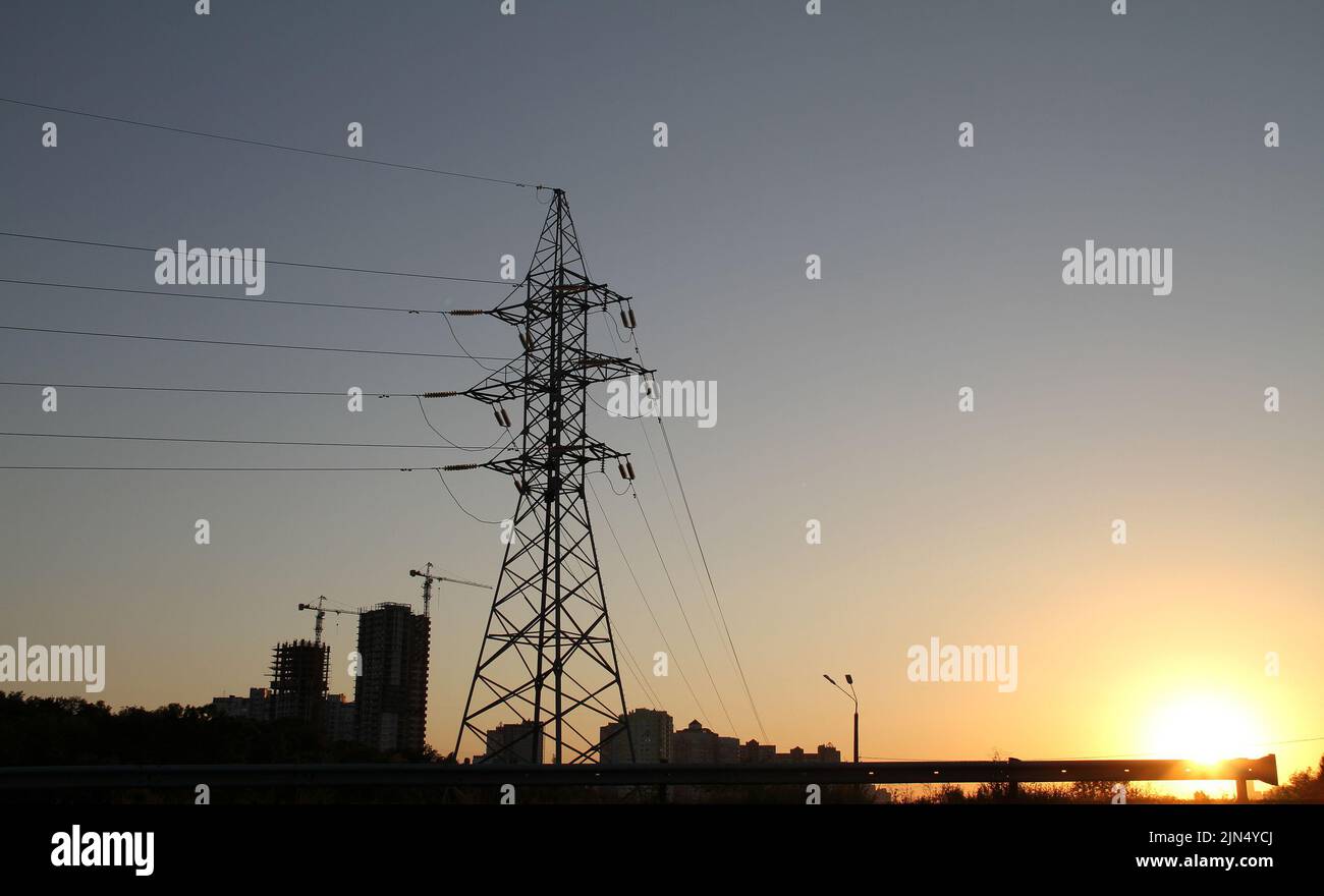 Silhouette of high voltage power line tower with building construction ...