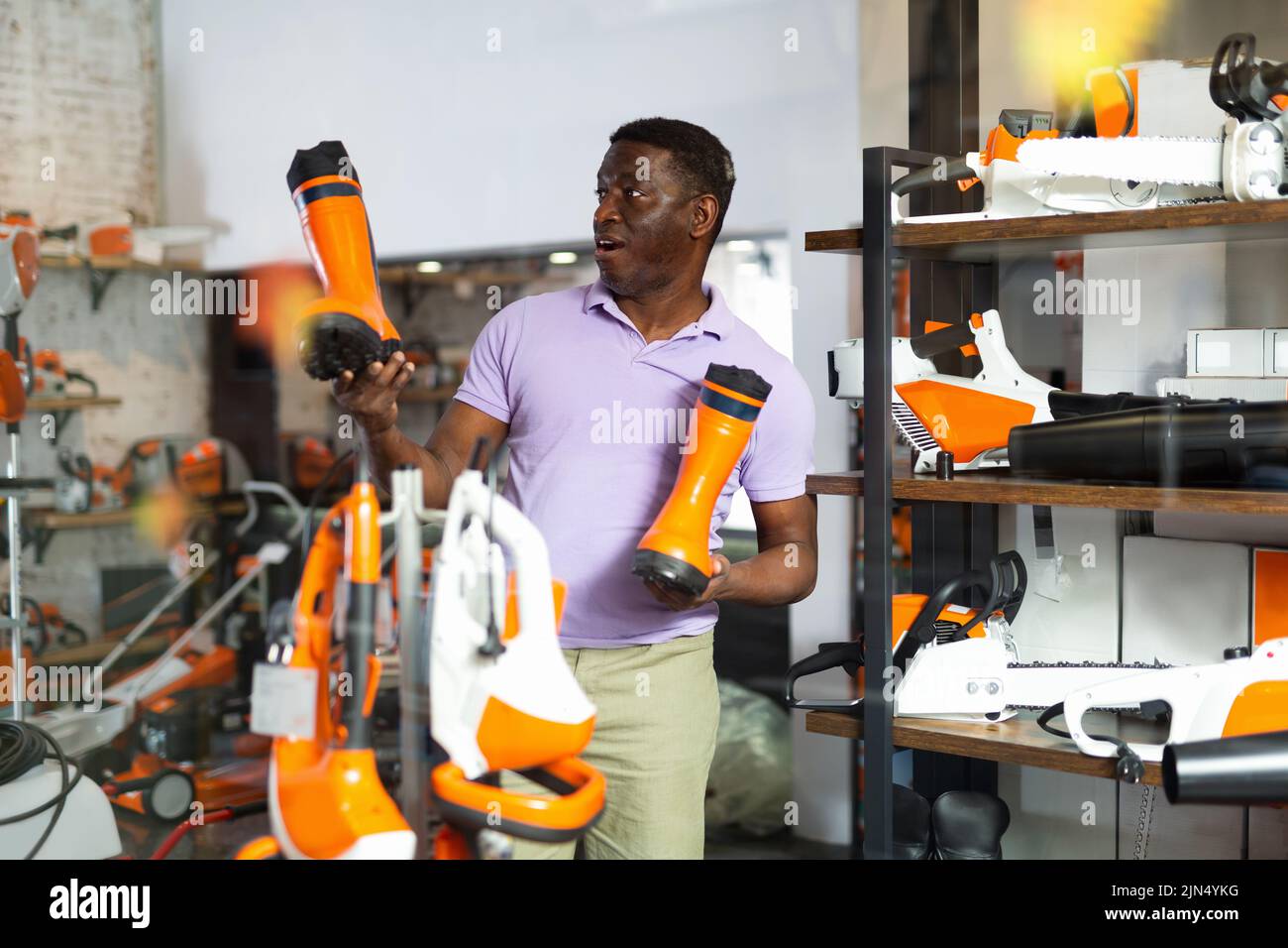 Man chooses rubber boots at garden supply store Stock Photo - Alamy