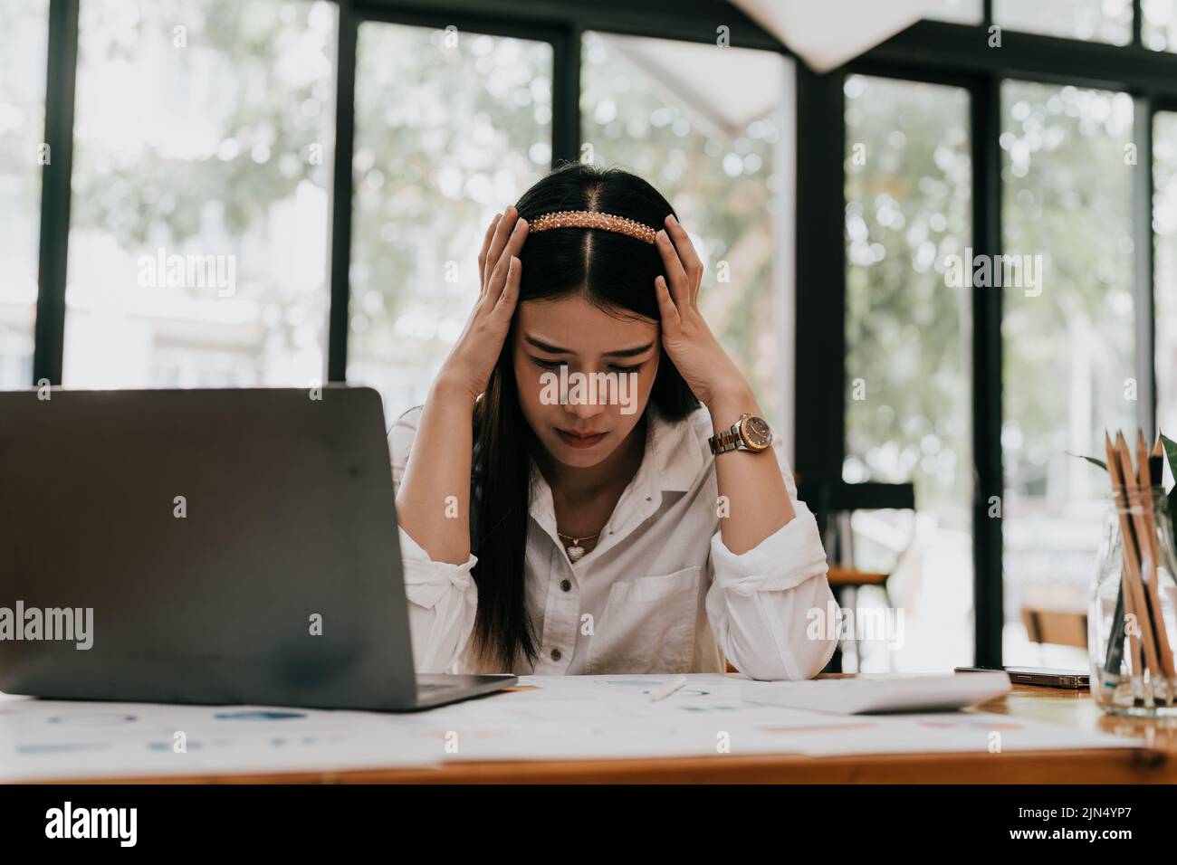Upset woman touching head using calculator and laptop for calculating ...