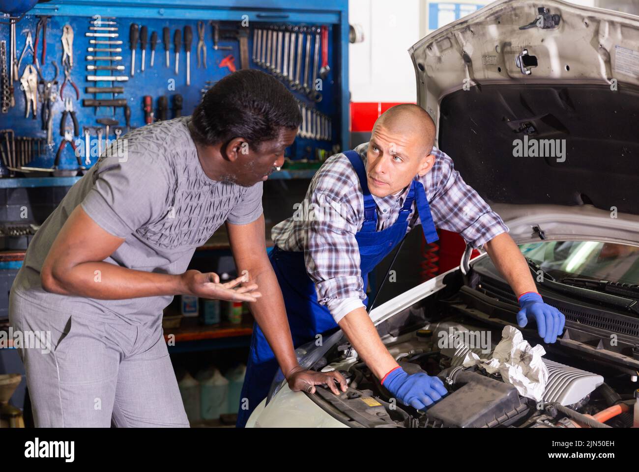 Mechanic and assistant working at auto repair Stock Photo - Alamy