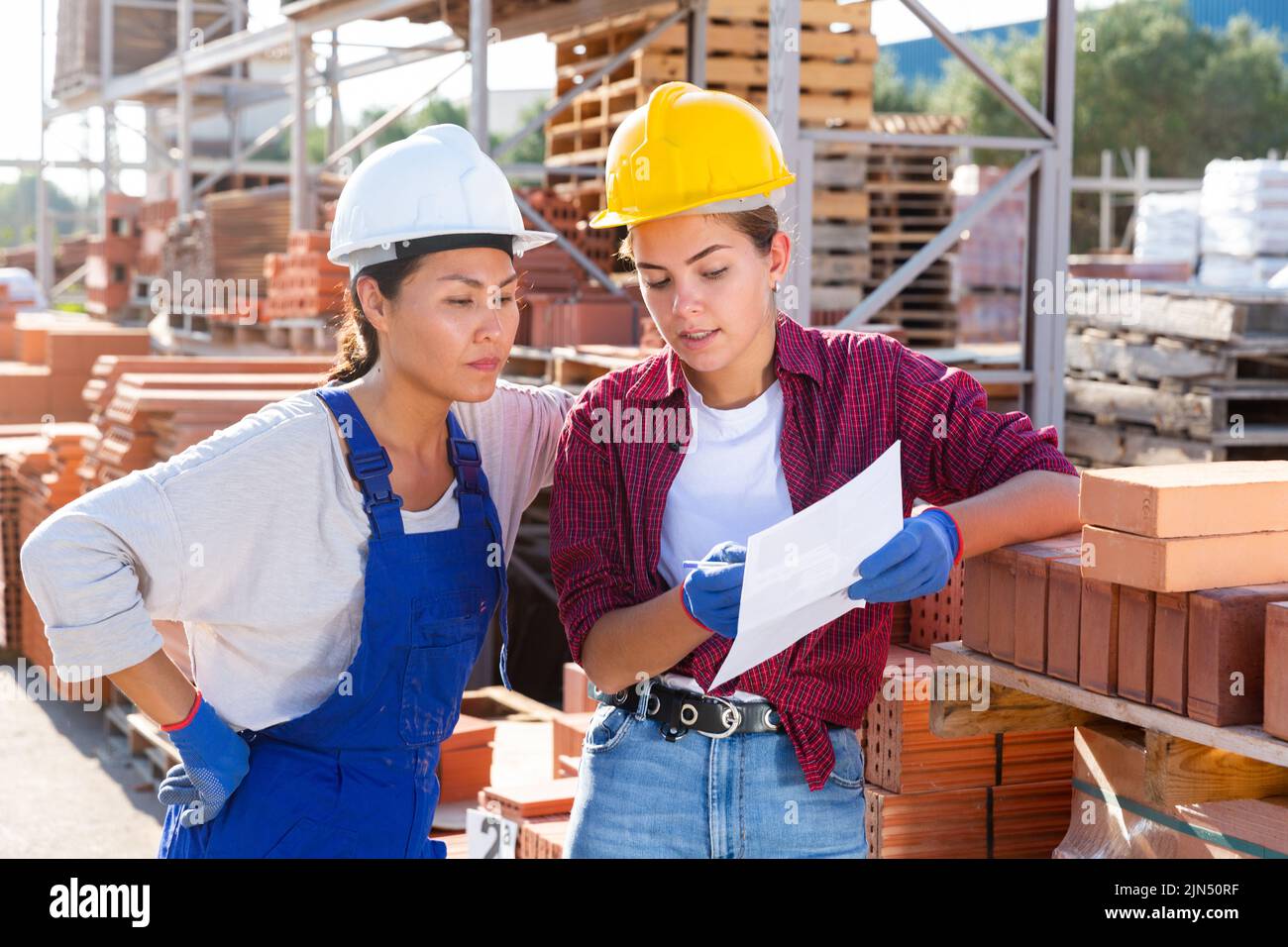 Female builders talking in outdoor storage Stock Photo - Alamy