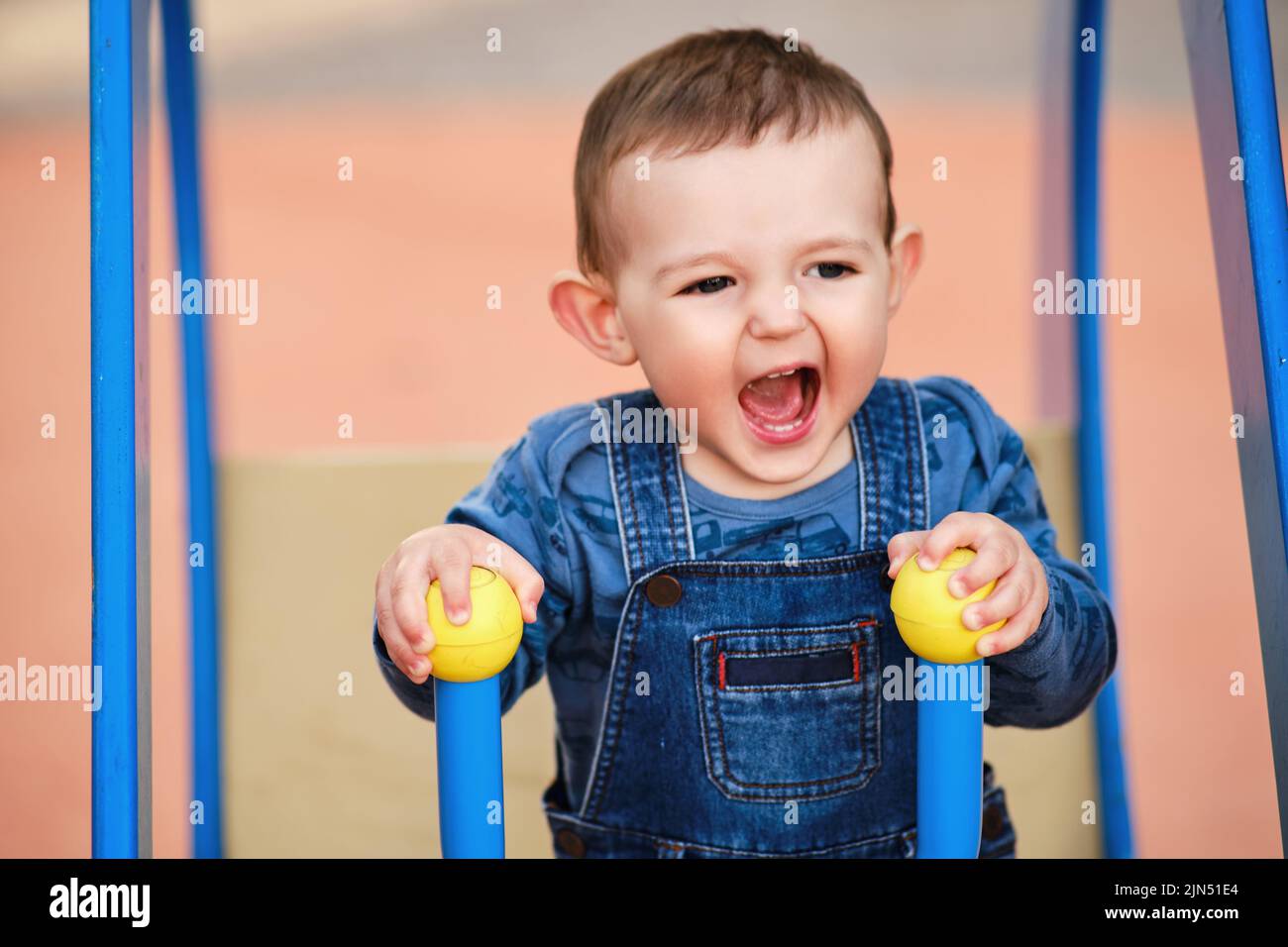 Happy child sitting behind the wheel of a toy tractor car in the ...