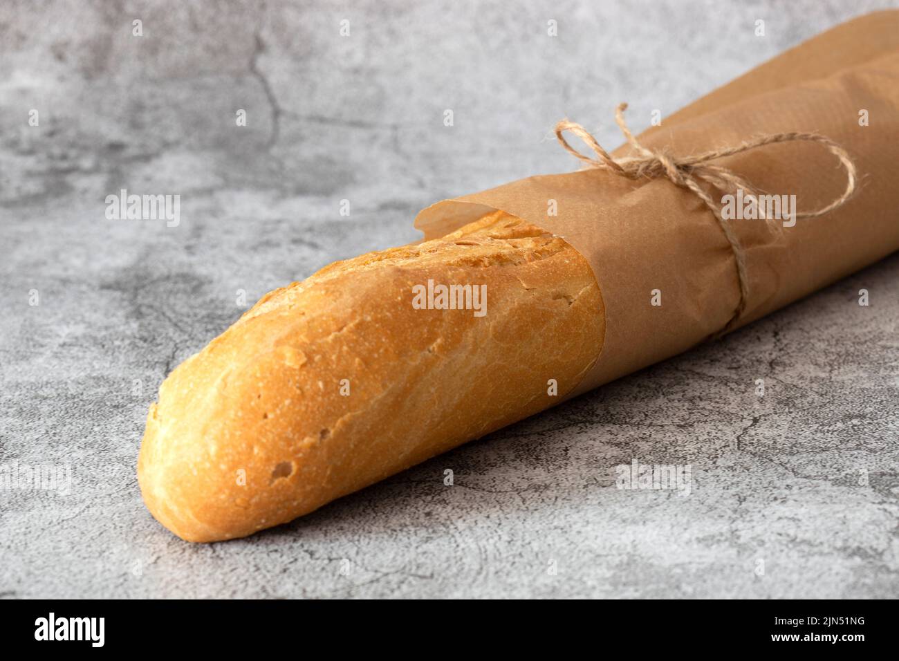 Baguette bread, french stick, wrapped in brown paper tied with string ...