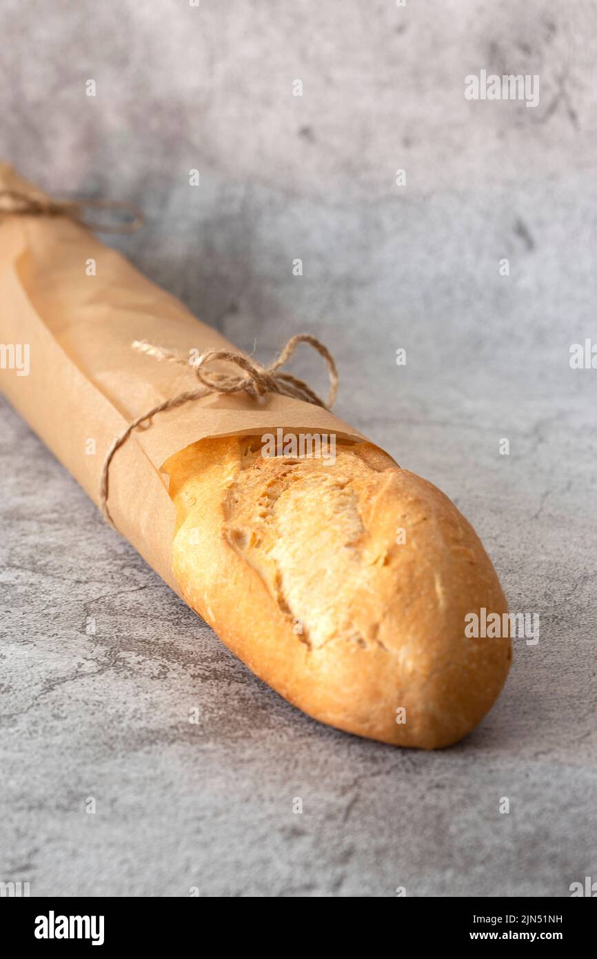 Baguette bread, french stick, wrapped in brown paper tied with string ...