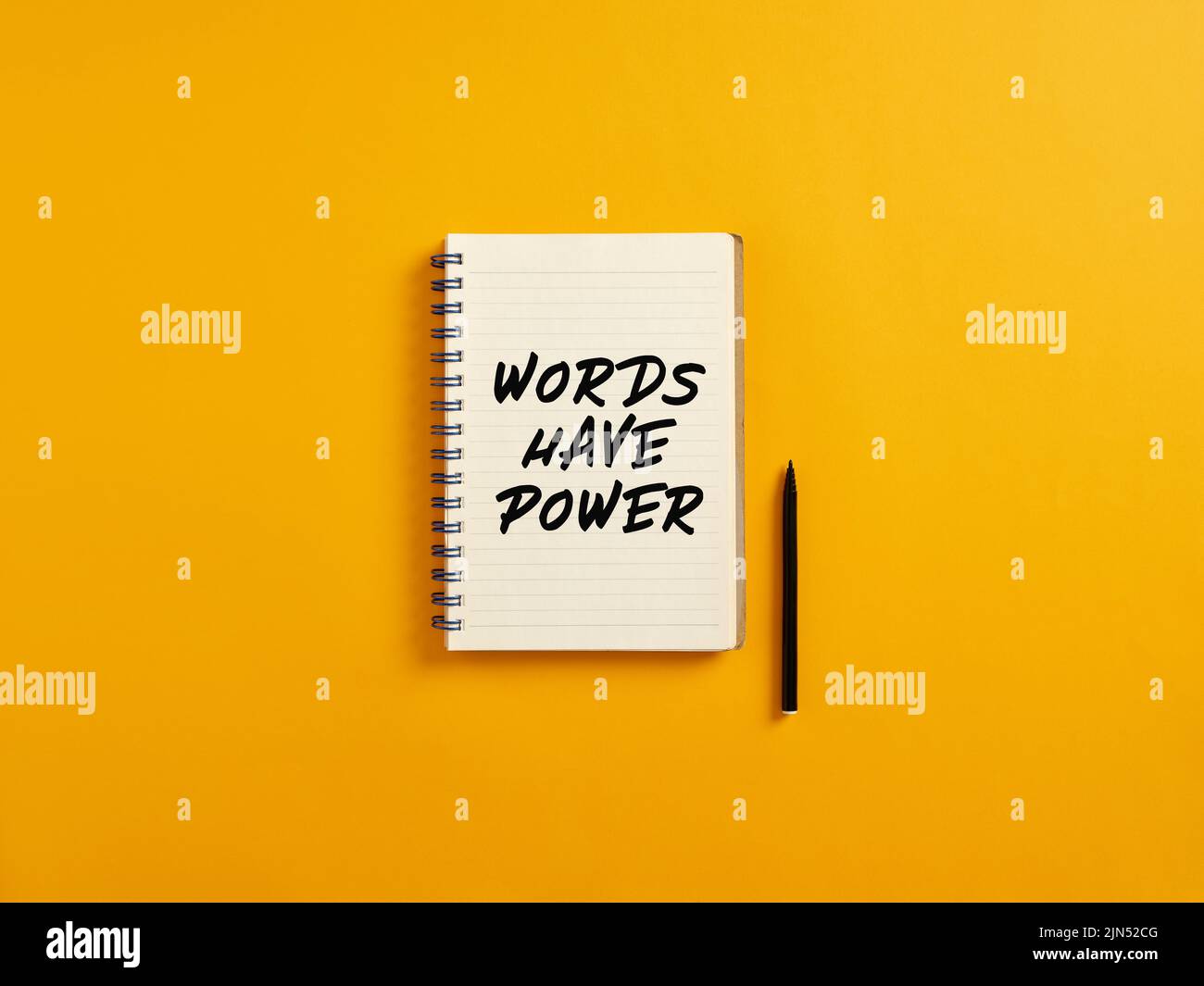 Notepad and black pen on yellow background with the message words have ...