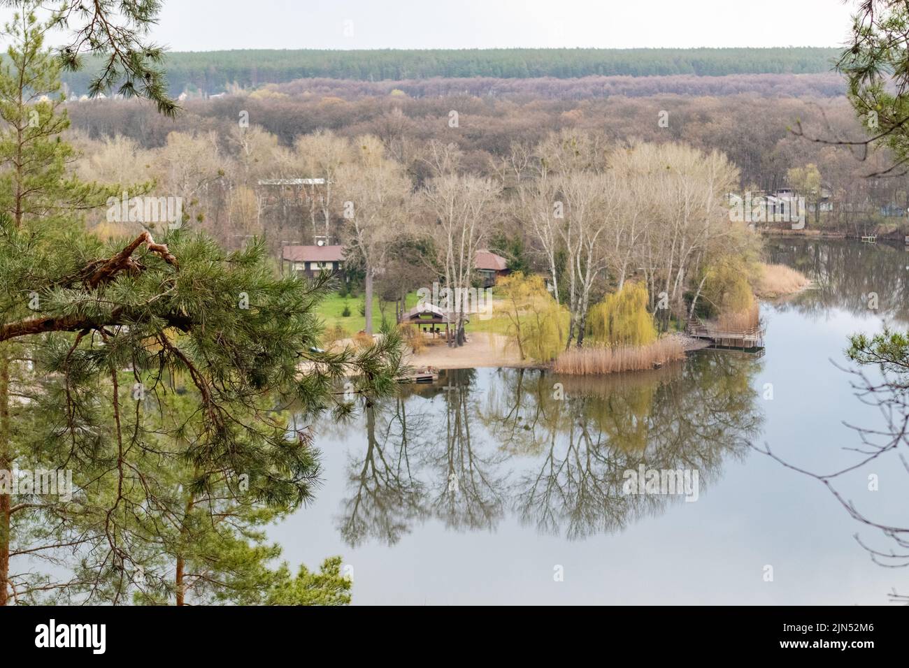 Spring view on river with recreation area and pine tree branch close-up ...
