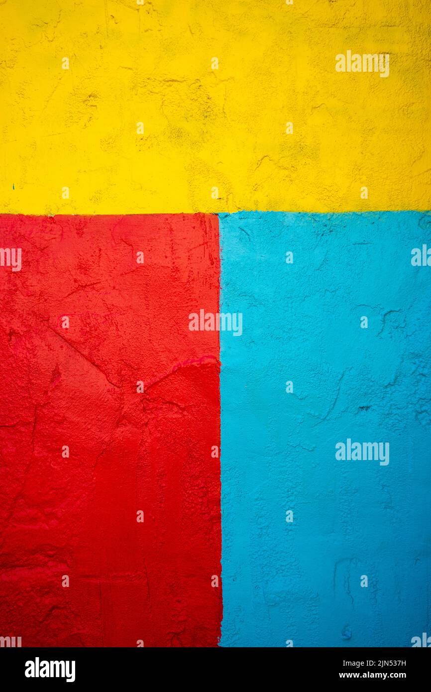 The textured wall is painted in red-turquoise and yellow bright and ...