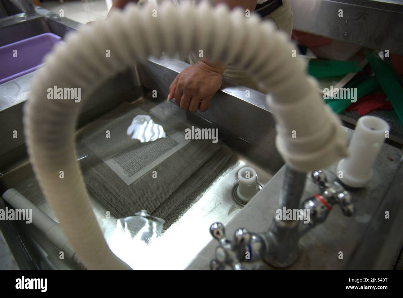 A scientist doing maintenance work on a valuable page of a book by ...