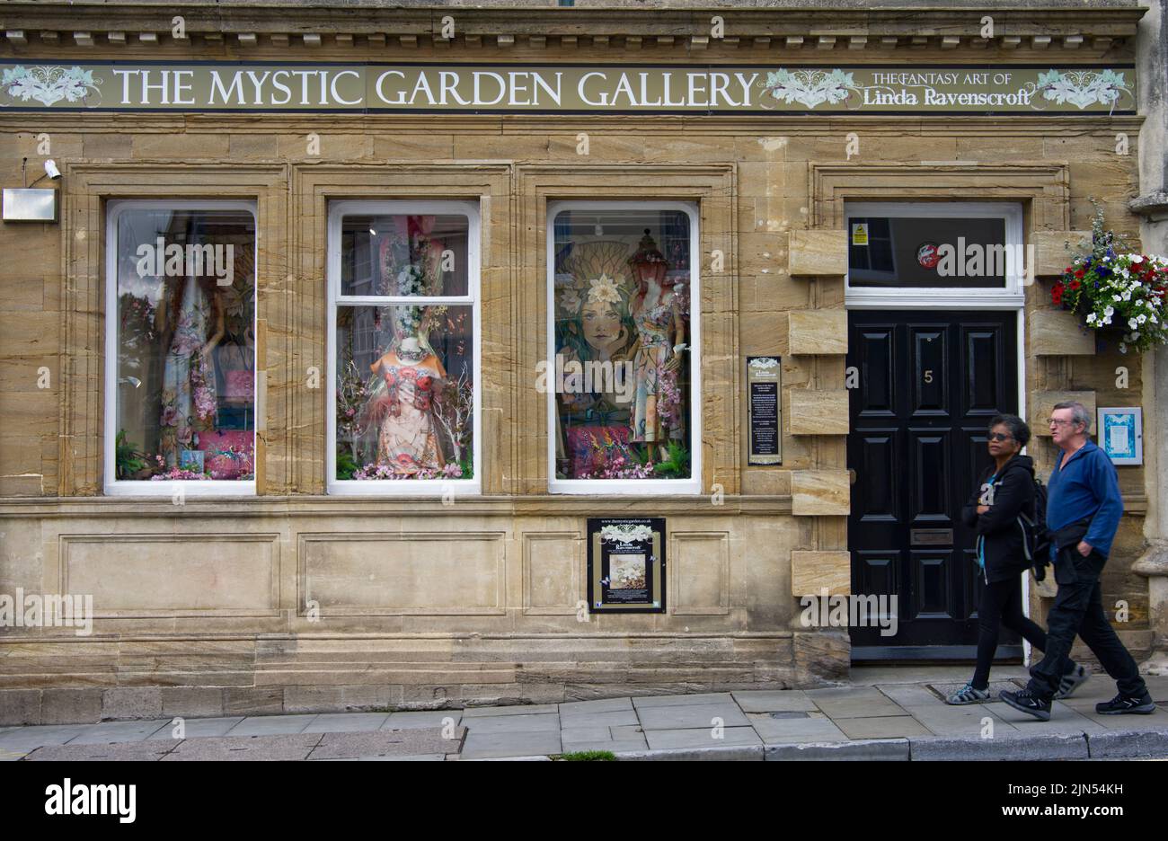 A couple walking past a new age shop on Glastonbury's High-Street Stock ...