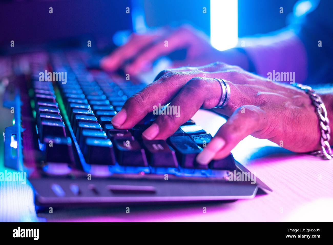 Close up shot of hands of gamer using neaon light keyboard for playing ...