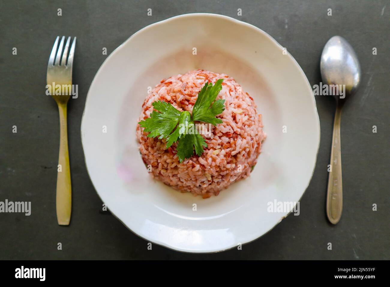 Red steamed rice or nasi merah served in plate isolated on black ...