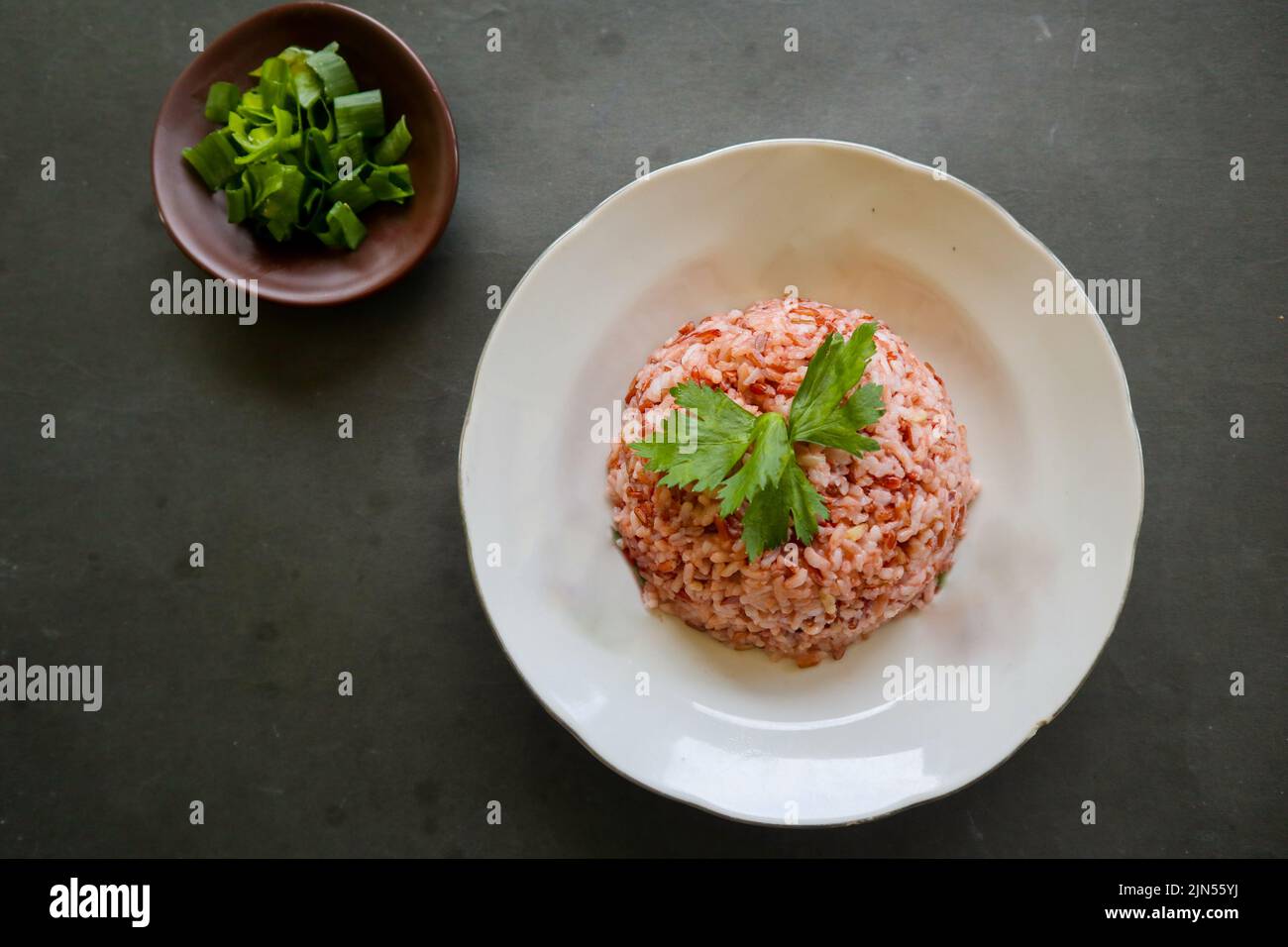 Red steamed rice or nasi merah served in plate isolated on black ...