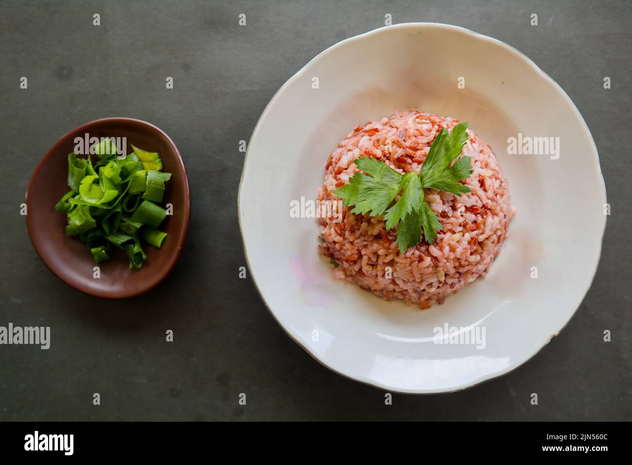 Red steamed rice or nasi merah served in plate isolated on black ...