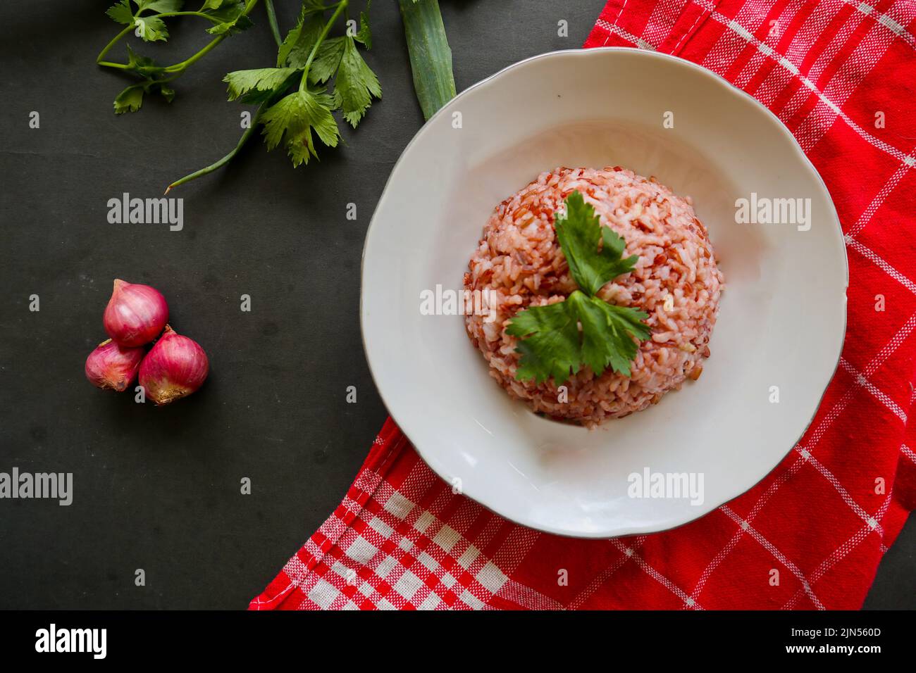 Red steamed rice or nasi merah served in plate isolated on black ...