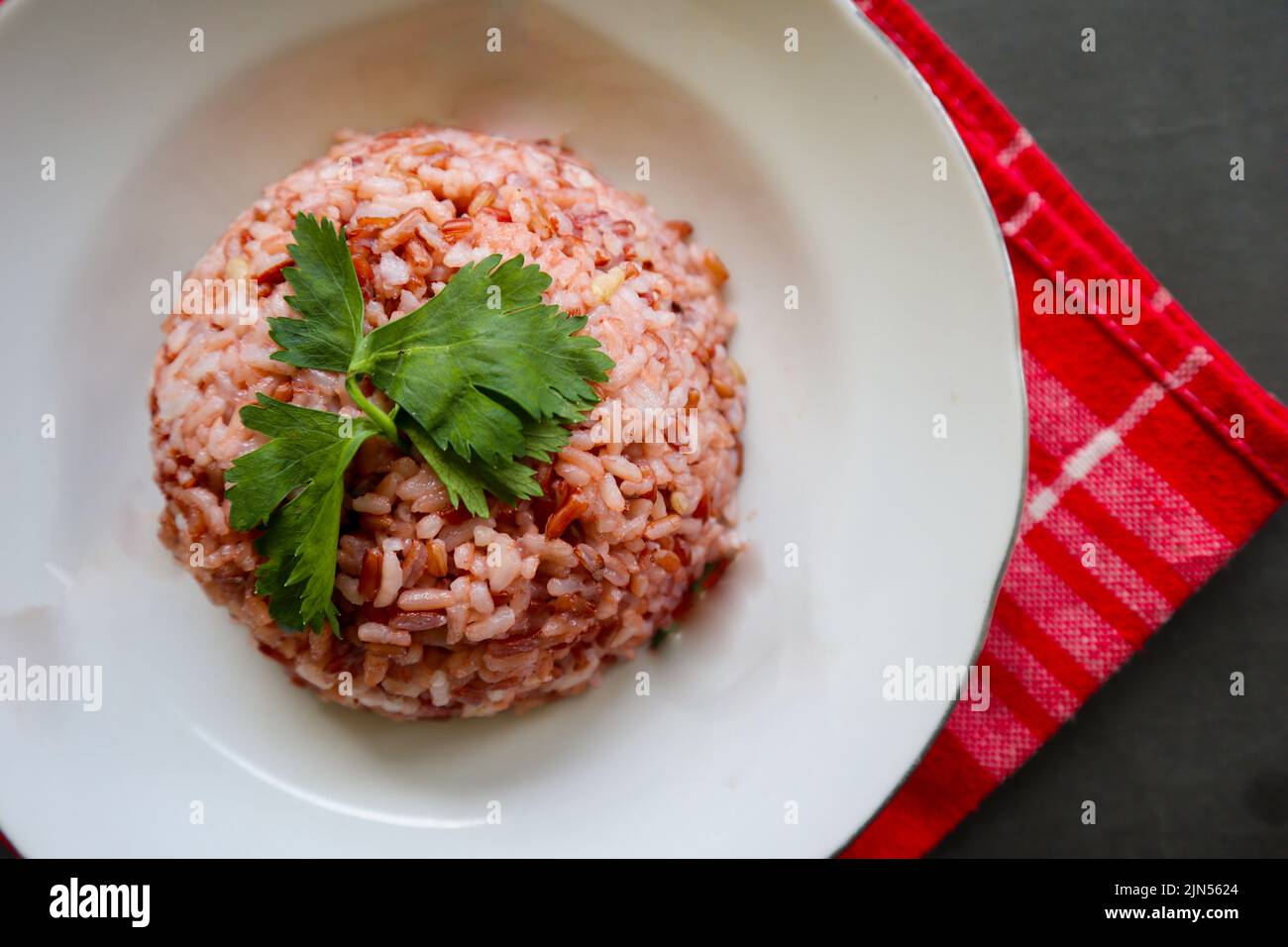 Red steamed rice or nasi merah served in plate isolated on black ...
