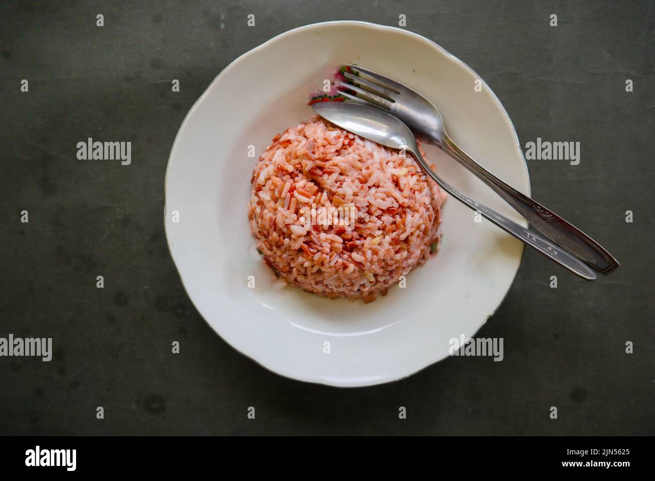 Red steamed rice or nasi merah served in plate isolated on black ...