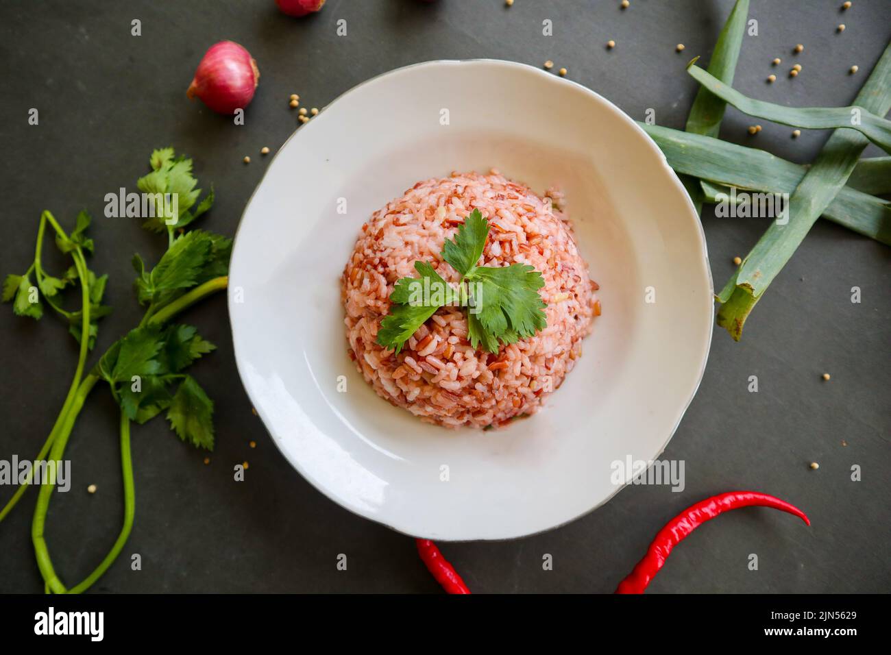 Red steamed rice or nasi merah served in plate isolated on black ...