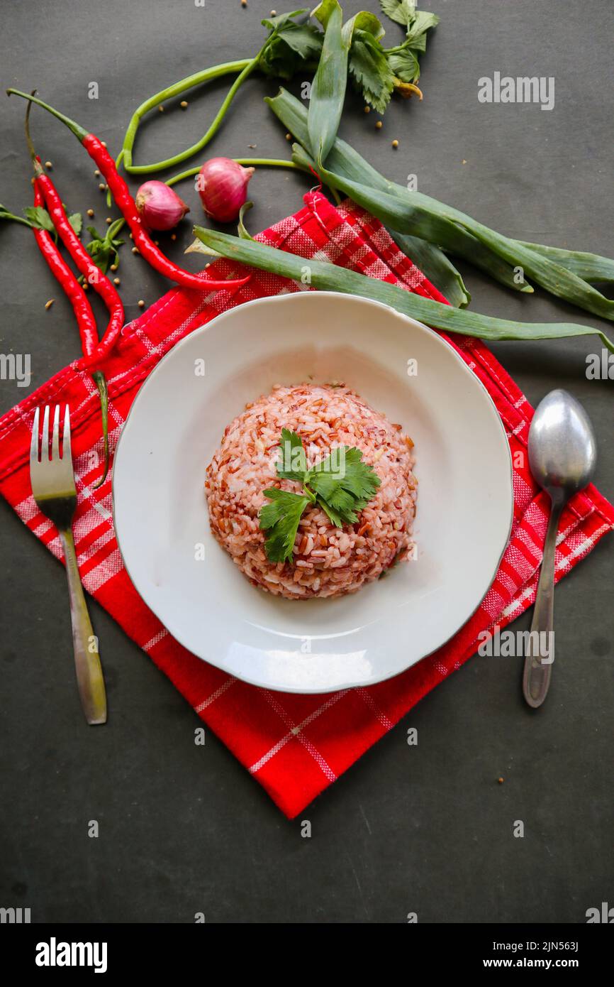Red steamed rice or nasi merah served in plate isolated on black ...