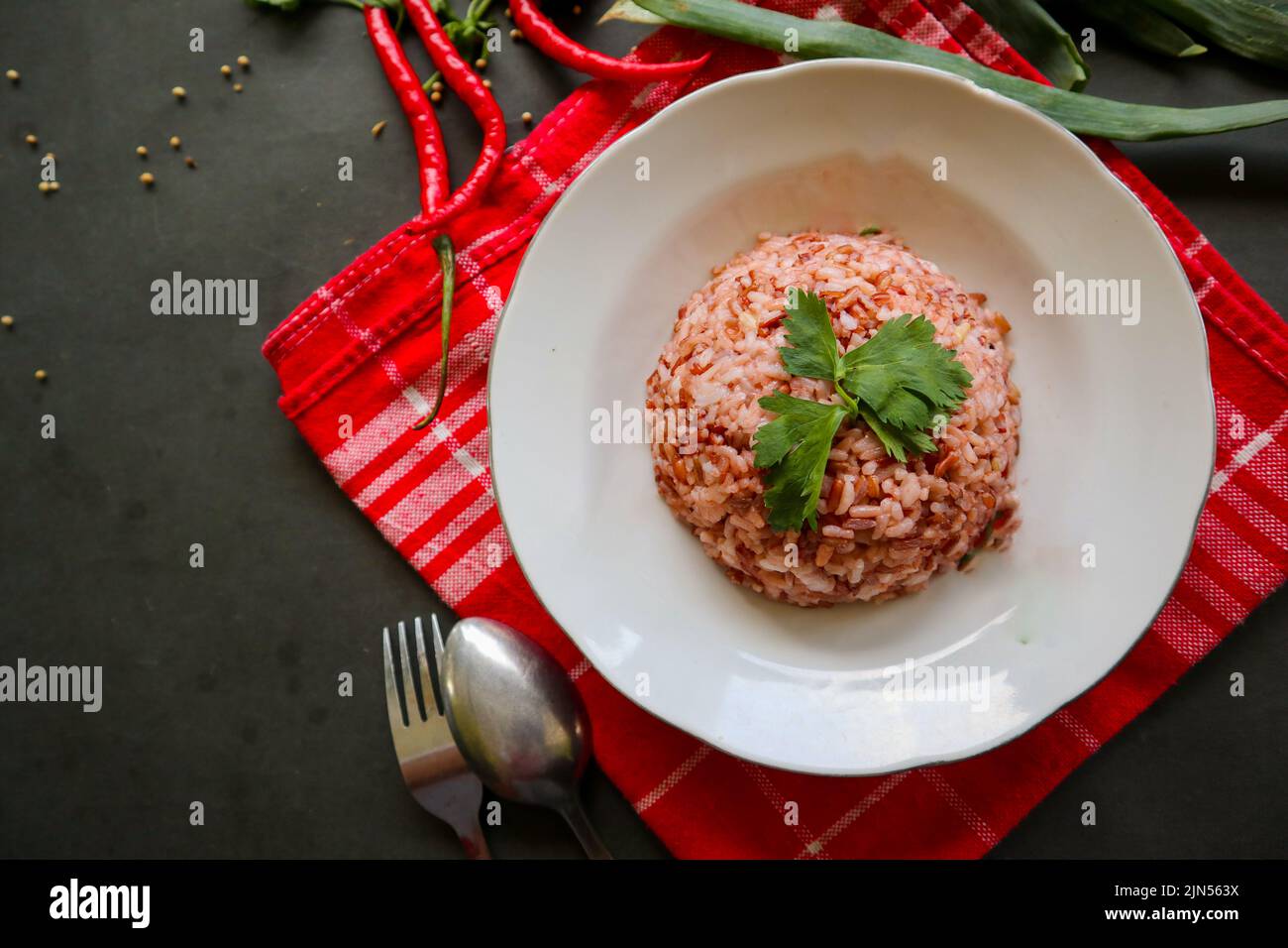 Red steamed rice or nasi merah served in plate isolated on black ...
