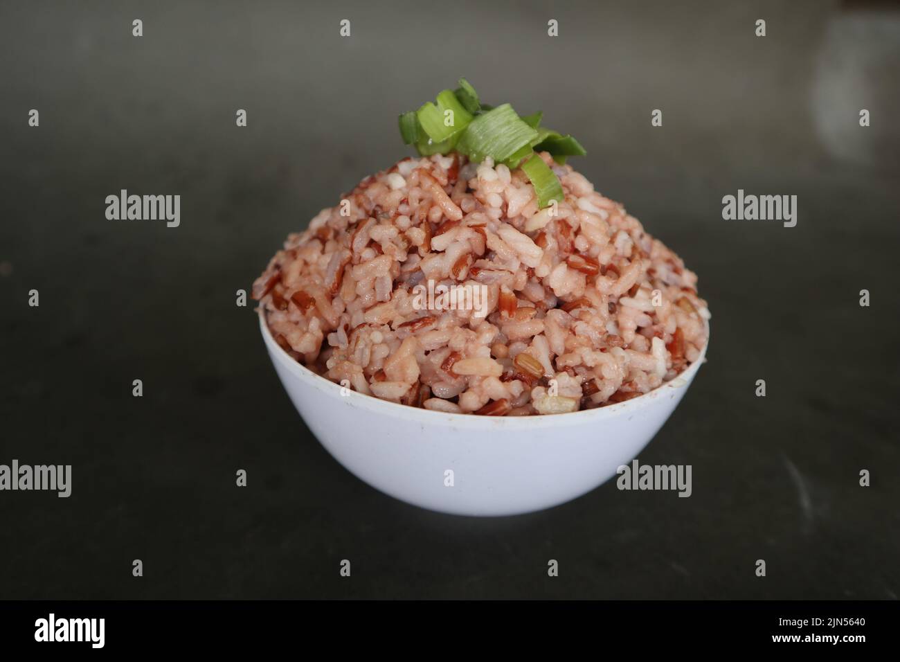 Red steamed rice or nasi merah served in plate isolated on black ...