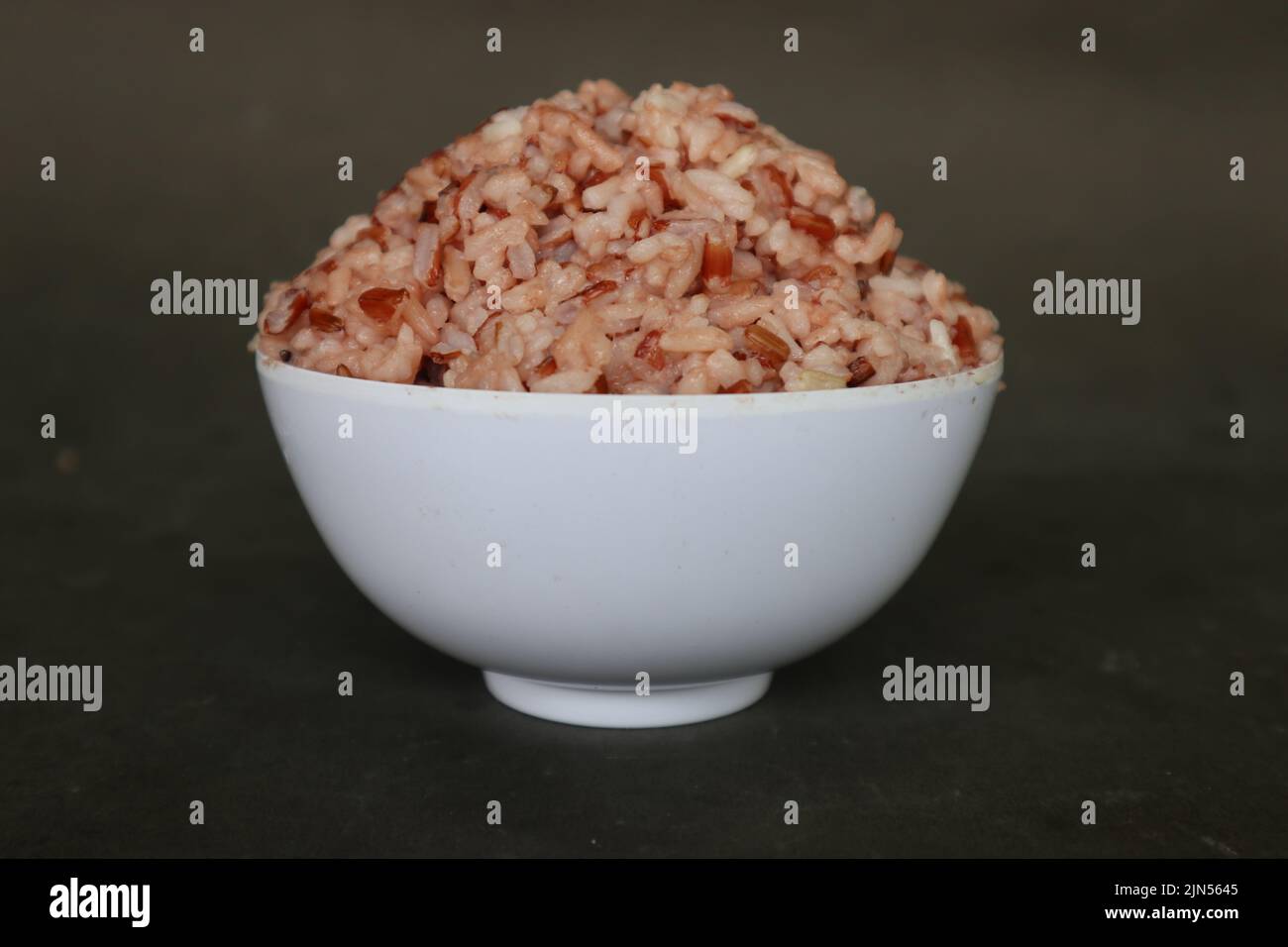 Red steamed rice or nasi merah served in plate isolated on black ...